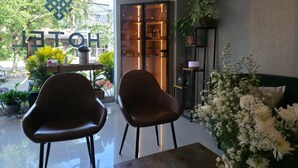 Um saguão de hotel com duas cadeiras marrons, uma vitrine de vidro e um vaso de plantas.