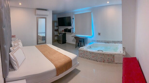 Quarto de hotel moderno com uma cama grande, banheiro separado com banheira, escrivaninha e uma cadeira.