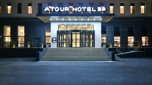 Entrada de hotel com uma placa indicando 'ATOUR HOTEL'.