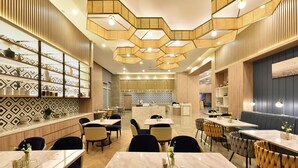 Restaurante moderno com luminárias de teto hexagonais, mesas de mármore e decoração de parede estampada.