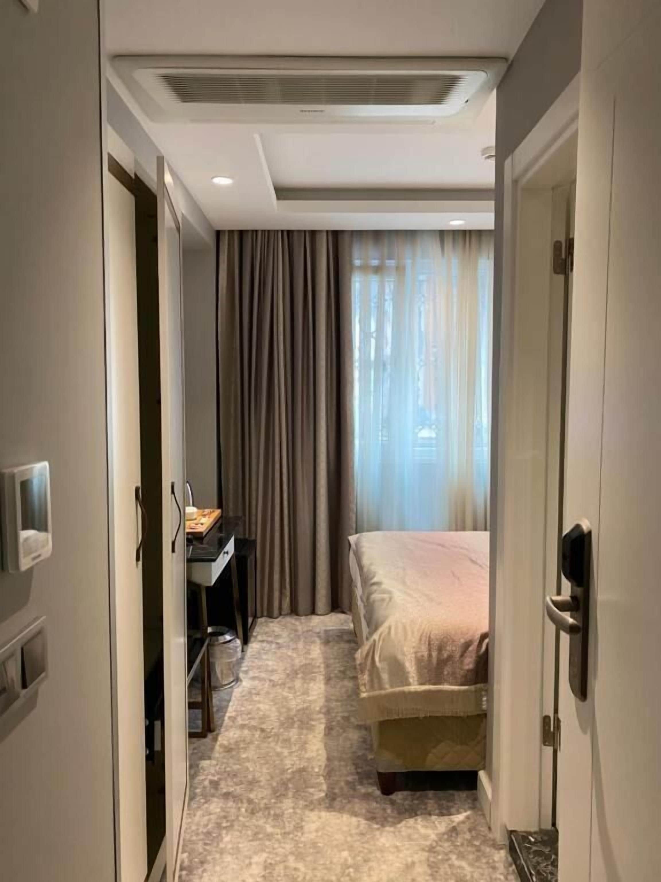 Quarto de hotel com cama, escrivaninha, guarda-roupa e banheiro.