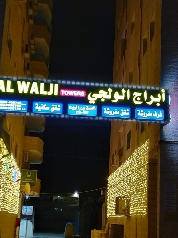 Placa para Al Walji Towers com texto iluminado em árabe e inglês, indicando o nome do edifício.