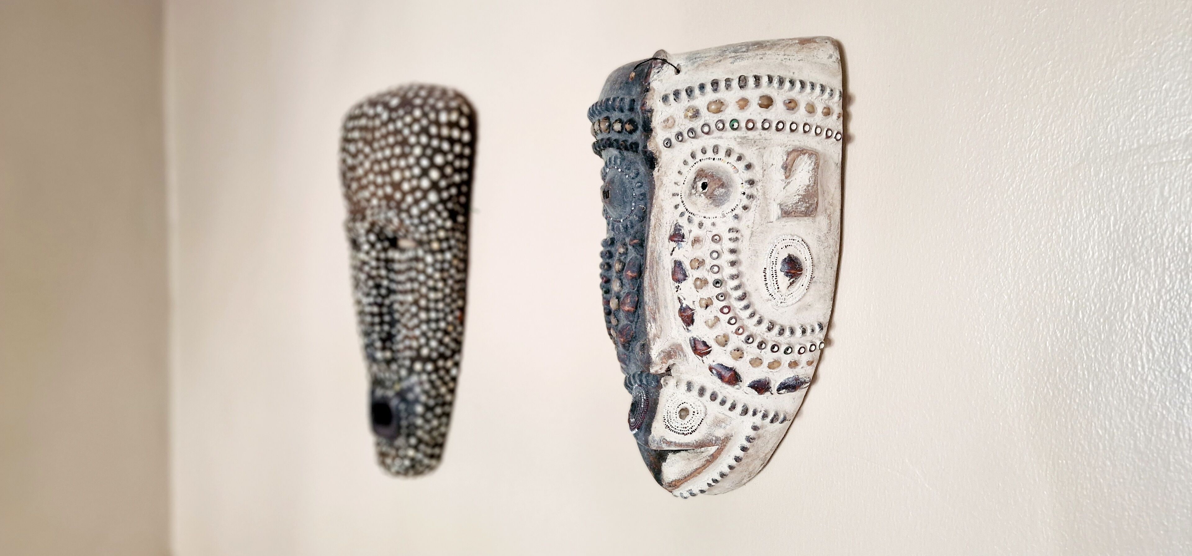 Duas esculturas fixadas na parede, com padrões e texturas detalhadas.