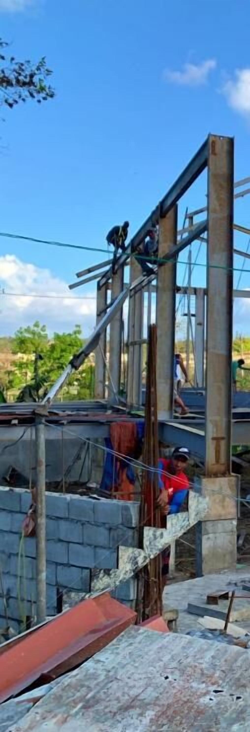 Um canteiro de obras com elementos estruturais aparentes e trabalhadores.