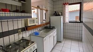 Uma cozinha compacta com fogão a gás, forno, micro-ondas e geladeira.