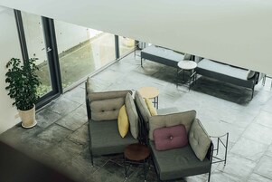 Uma área de estar moderna ao ar livre, com um sofá, uma mesa redonda pequena e um banco.