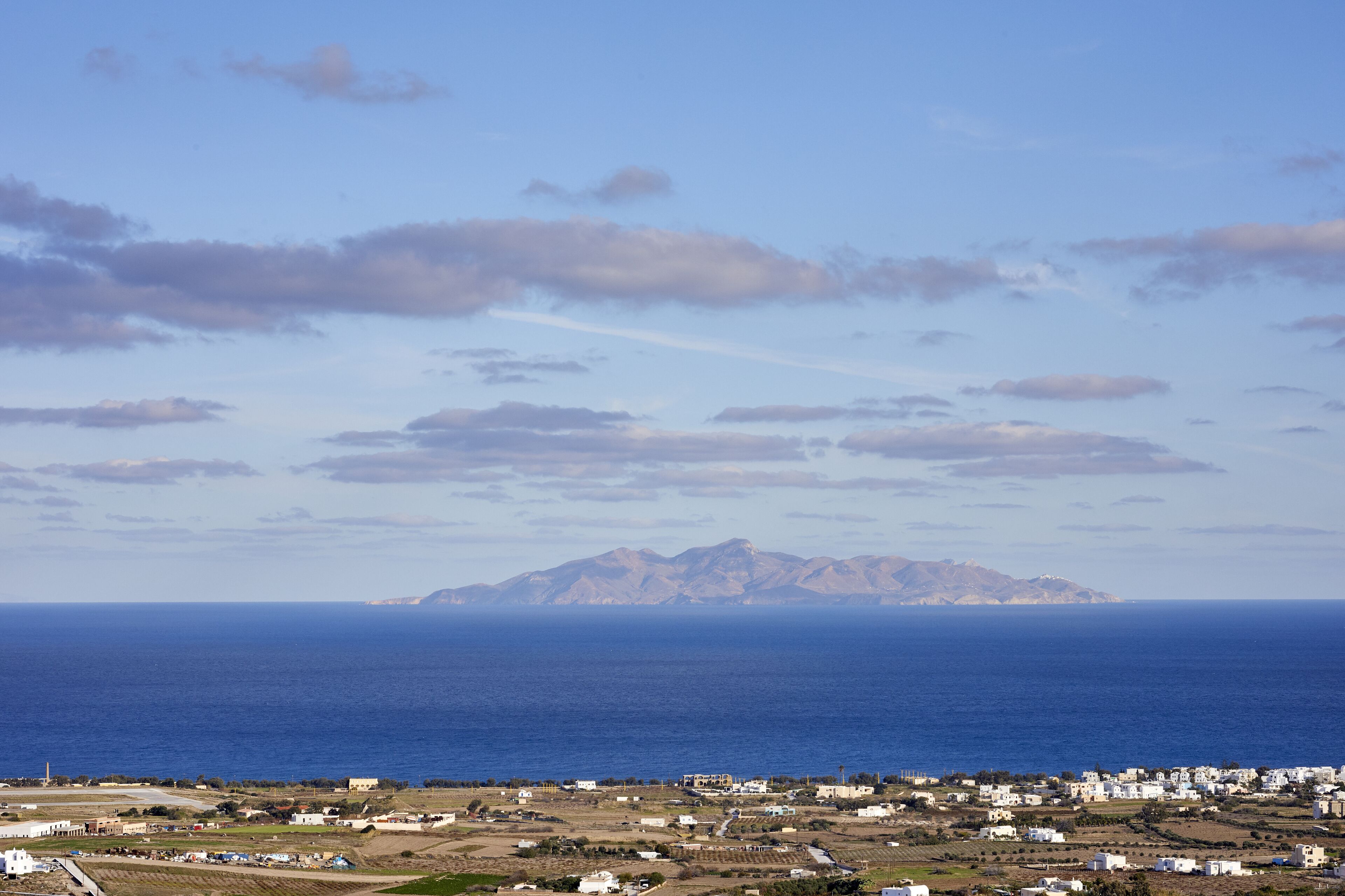 Uma vila costeira com vista para o mar e montanhas ao longe.