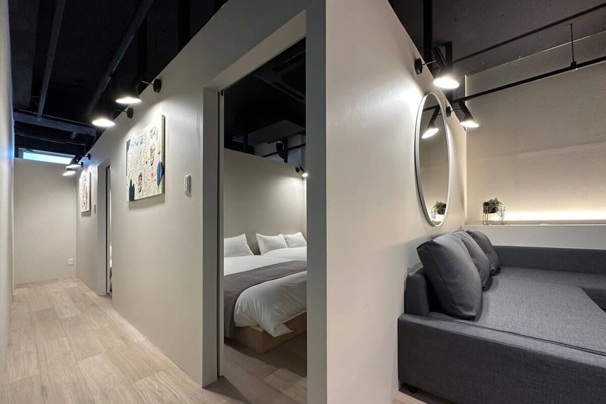 Quarto de hotel moderno com cama, sofá e um espelho grande.