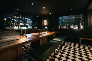 Uma área de bar com chão quadriculado, balcão de madeira e assentos.