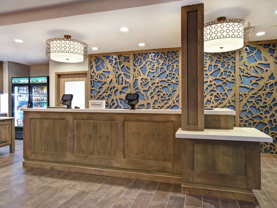 Uma área de recepção com um balcão de madeira, um minibar e uma parede decorativa com padrões elaborados.