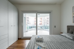 Quarto com cama, guarda-roupa e porta de vidro deslizante para área externa.