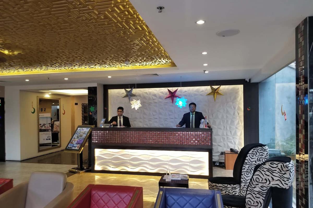 Uma área de recepção de hotel com design moderno, incluindo balcão de recepção, área de estar e elementos decorativos.