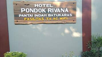 Uma placa de madeira com o nome de um hotel, seus serviços e comodidades.