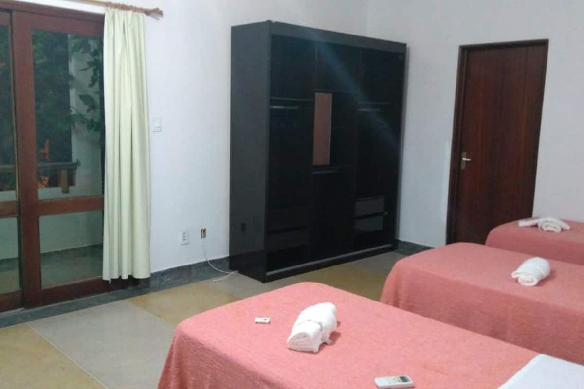 Quarto de hotel com duas camas, um guarda-roupa amplo, uma porta de correr de vidro e uma porta.