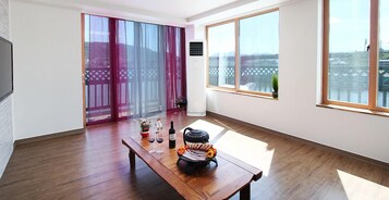 Um quarto espaçoso com piso de madeira, uma janela ampla com vista e uma porta deslizante com vista.