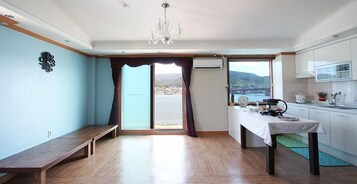 Cozinha moderna com vista para a água e colinas, área de jantar com bancos e um candelabro.