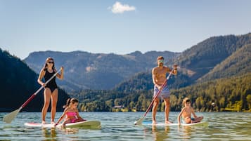 Um grupo de pessoas praticando paddleboard em um lago calmo, com montanhas ao fundo.