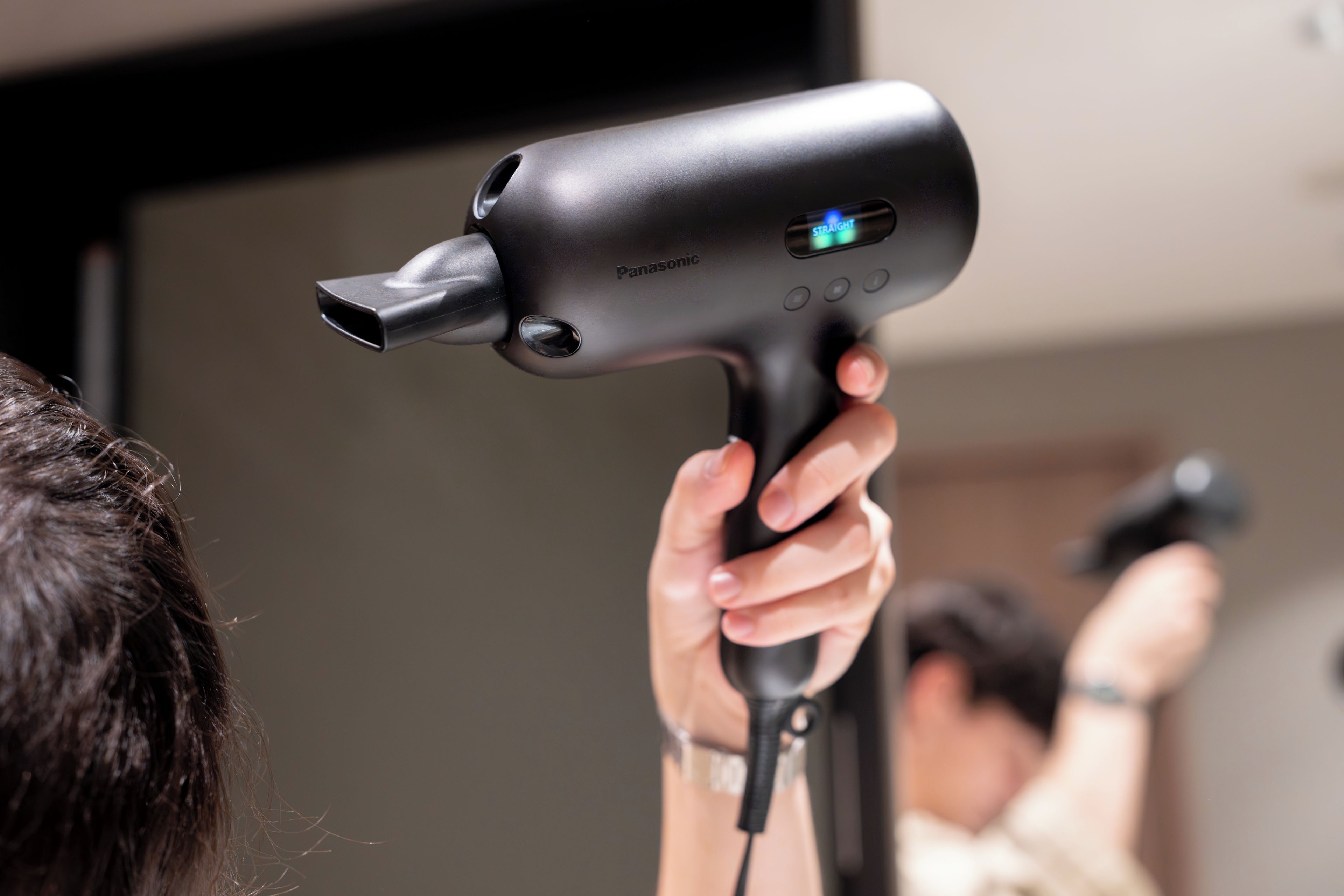 Uma pessoa segurando um secador de cabelo Panasonic.