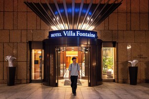 A entrada do HOTEL Villa Fontaine, com fachada curva e um letreiro sobre as portas.