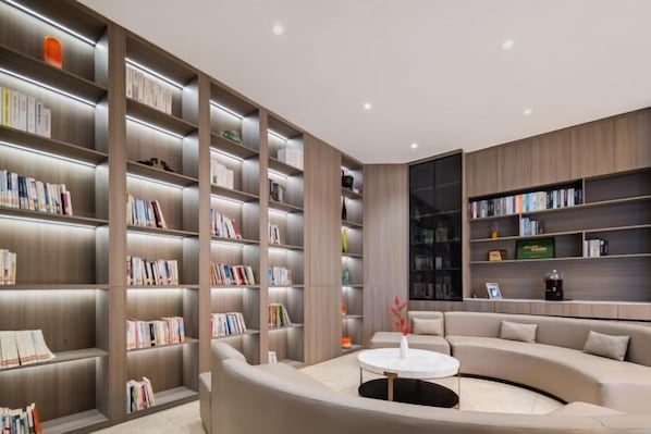 Uma biblioteca moderna com estantes, uma área de estar em curva e uma mesa redonda.