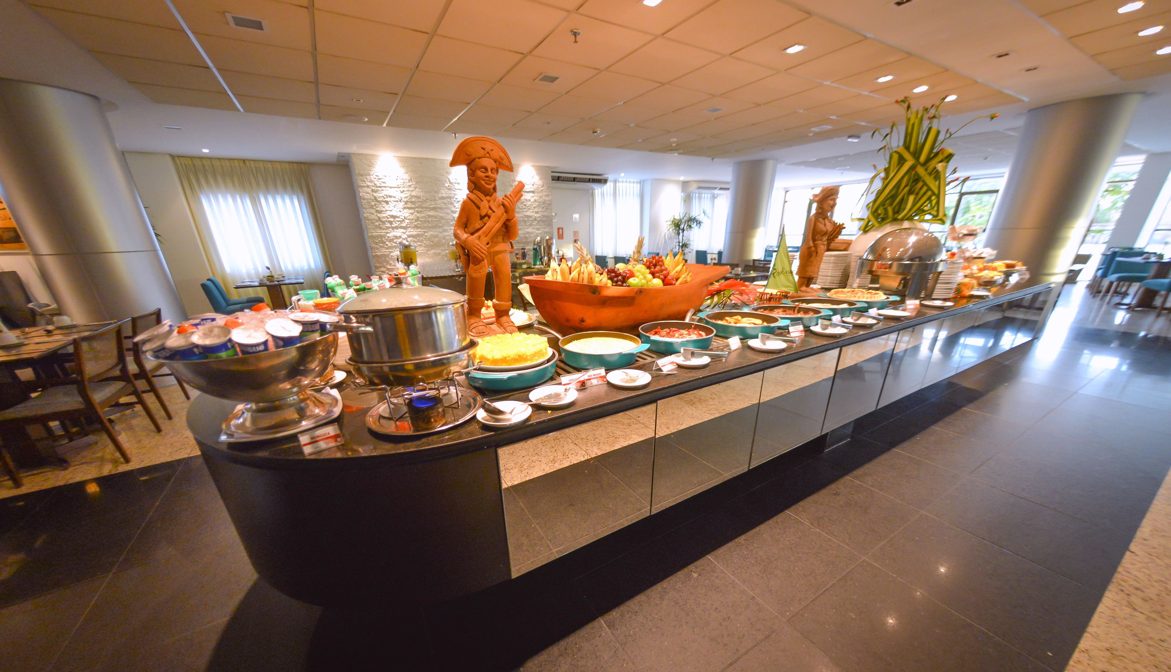Buffet com diversos alimentos e uma estátua de uma pessoa.