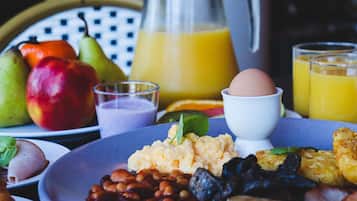 Disposição de café da manhã com ovos, torradas, feijão e frutas.
