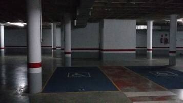 Uma garagem de estacionamento com pilares brancos, faixas vermelhas e brancas, e vagas para deficientes azuis.