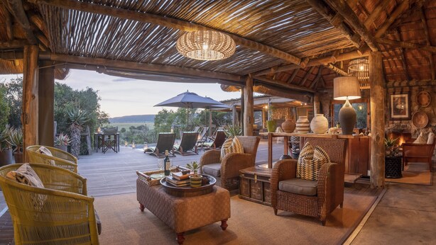 Um espaço de estar aconchegante com móveis de vime, um telhado de palha e vista para o exterior.