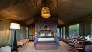 Um quarto espaçoso com cama de dossel, um espaço para sentar e uma mesa de jantar.
