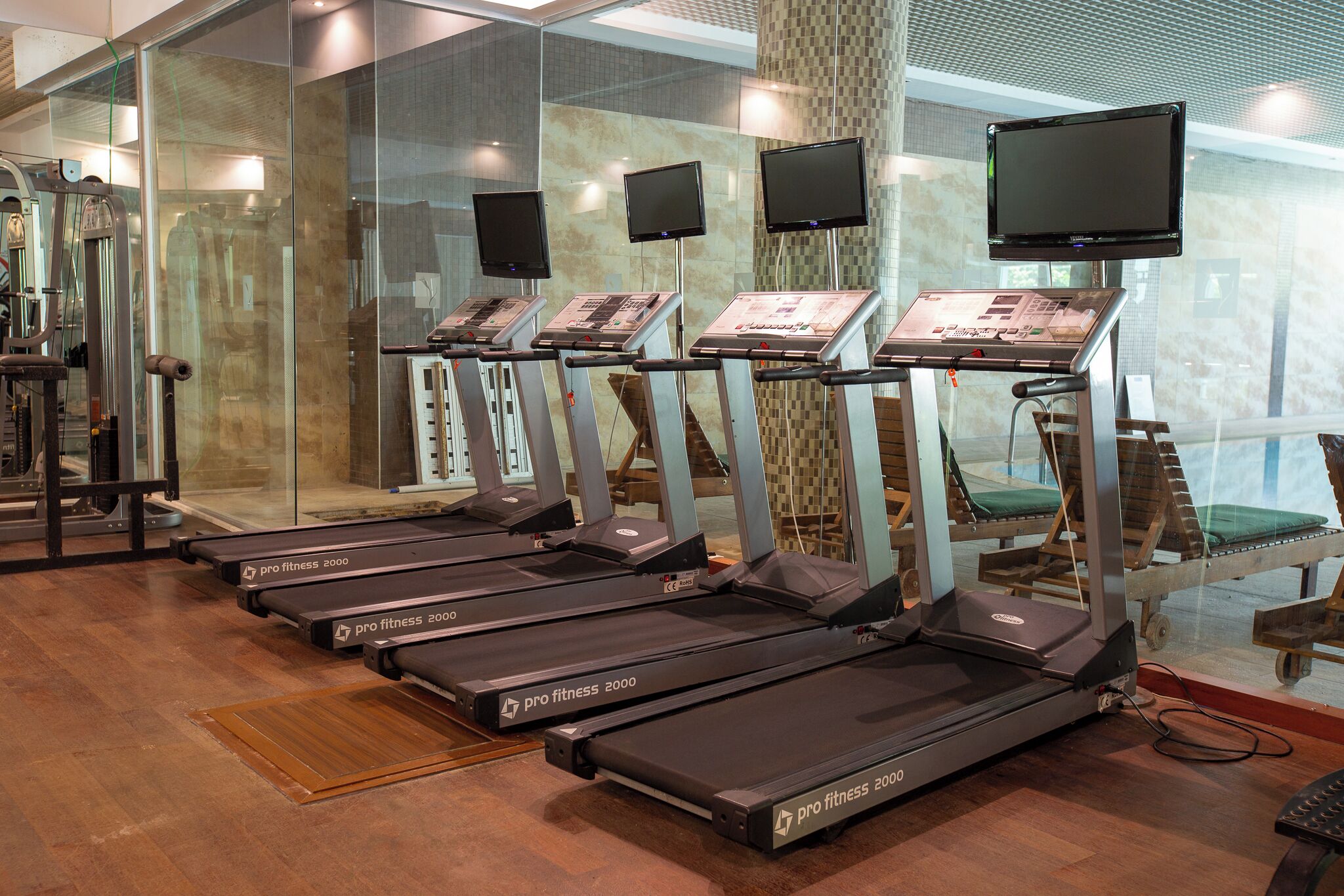 Uma academia com esteiras, aparelhos de musculação e estações de exercícios.