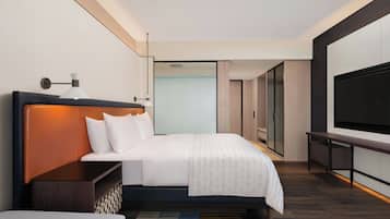 Quarto de hotel moderno com uma cama grande, uma TV e uma escrivaninha.