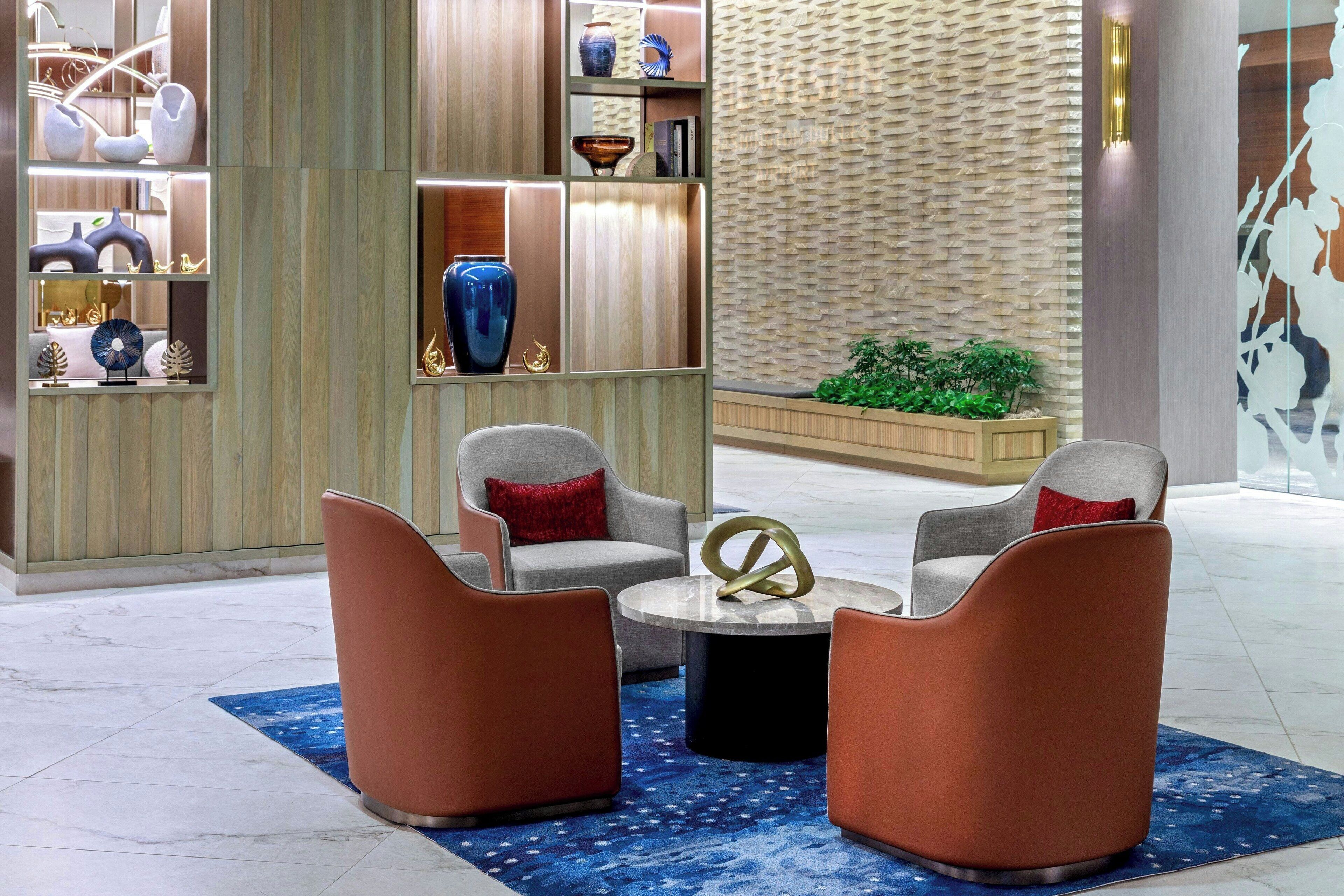 Um hall moderno com assentos, uma parede decorativa e um espaço com plantas.