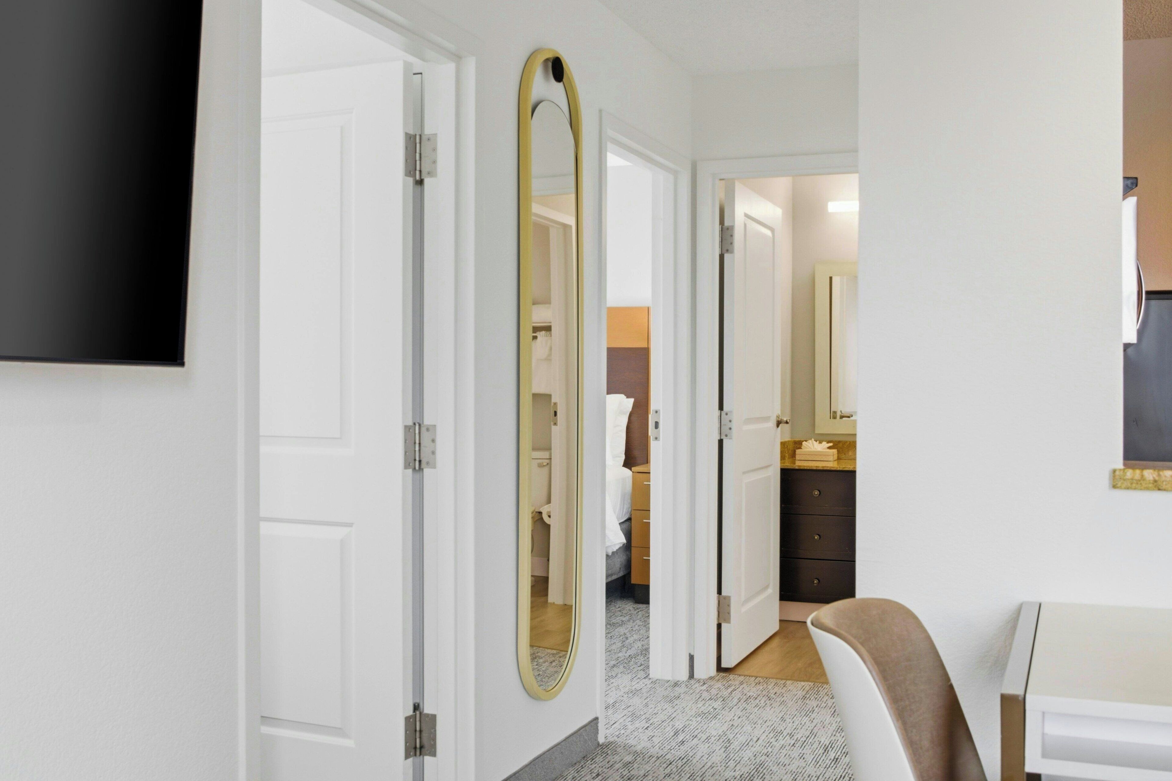 Quarto de hotel com televisão de tela plana, um espelho grande, uma cama, cômoda e escrivaninha.