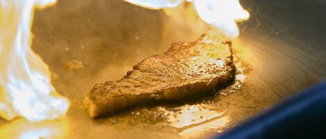 Um bife sendo grelhado em uma frigideira.