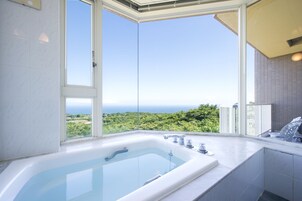 Casa de banho moderna com uma banheira grande, vista para o oceano e varanda com grade.