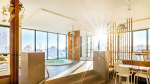 Interior moderno de hotel com vista para a cidade, hidromassagem e área de jantar com cadeiras brancas.