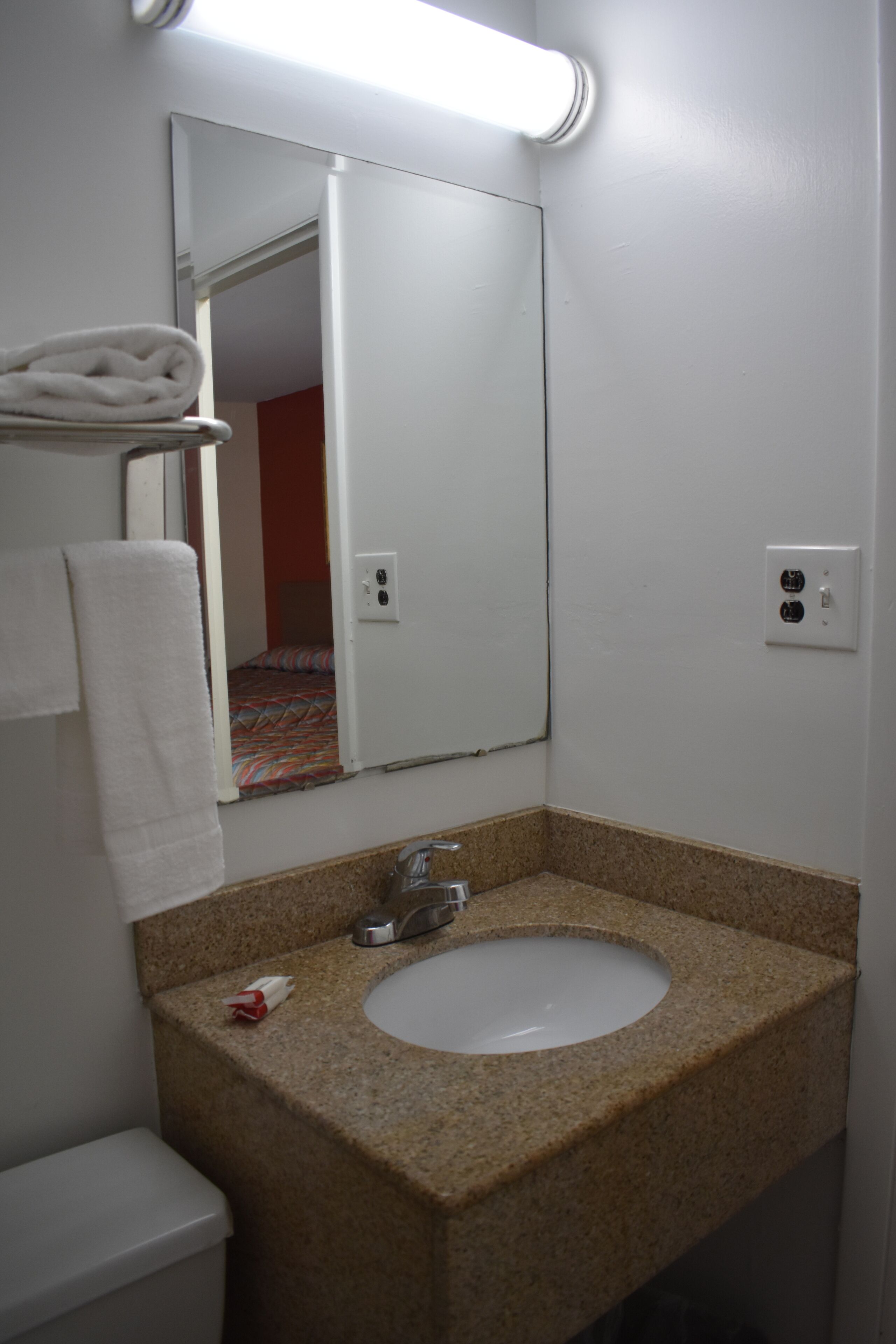 Casa de banho com lavatório branco, espelho e porta-toalhas.