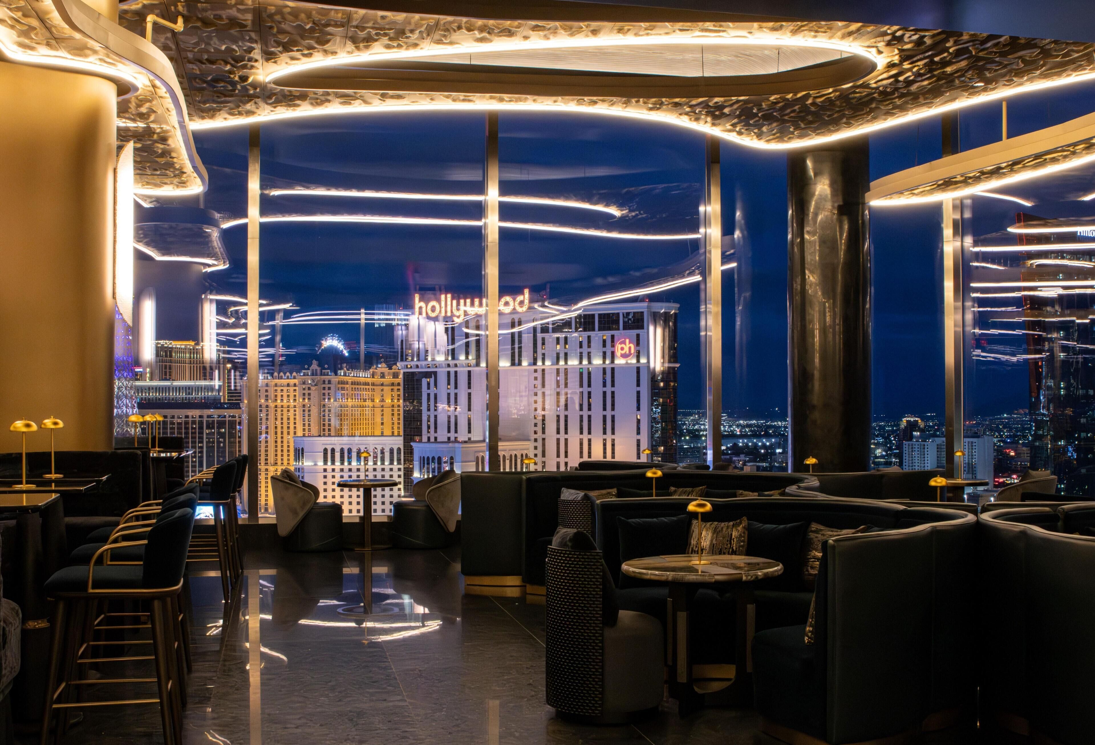 Um interior moderno com vista para o letreiro de Hollywood, com móveis elegantes e iluminação ambiente.
