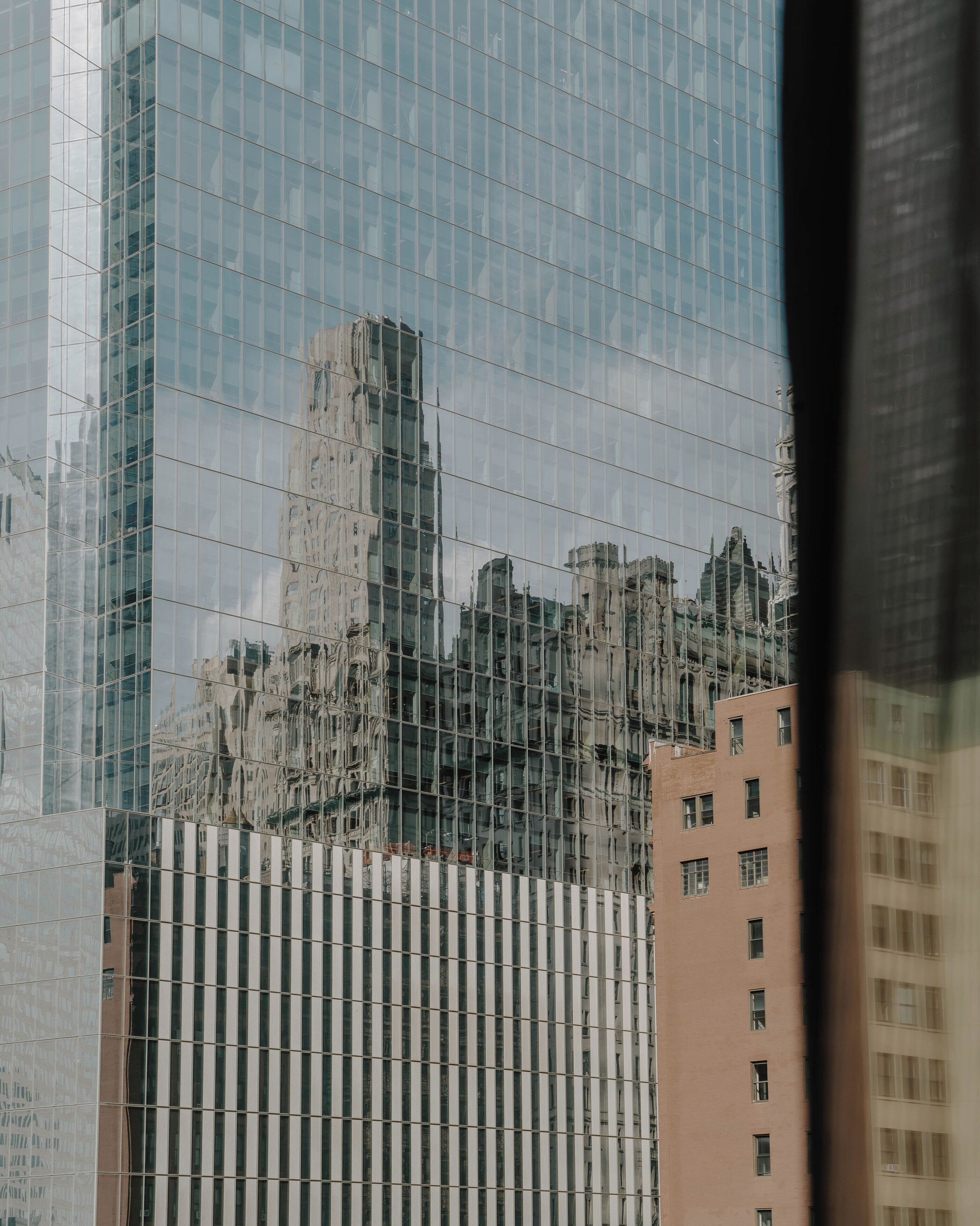 Um edifício moderno de vidro com fachada em grade que reflete edifícios ao redor.