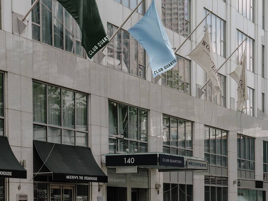 Um edifício moderno com várias bandeiras, incluindo 'Club Quartes' e 'World Center Hotel'.