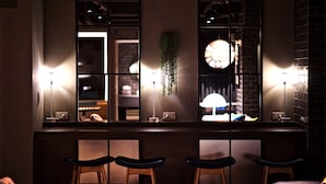 Uma área de bar com três banquetas, uma planta pendente e um relógio na parede.