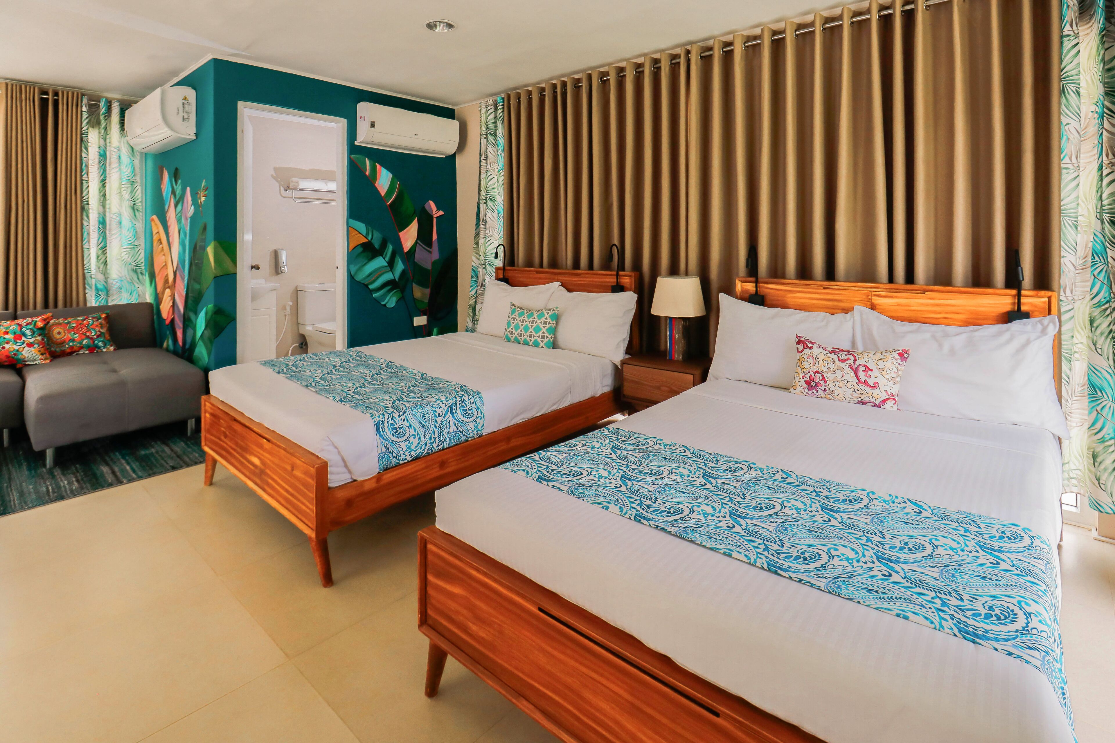 Quarto de hotel com duas camas, um sofá e um banheiro.