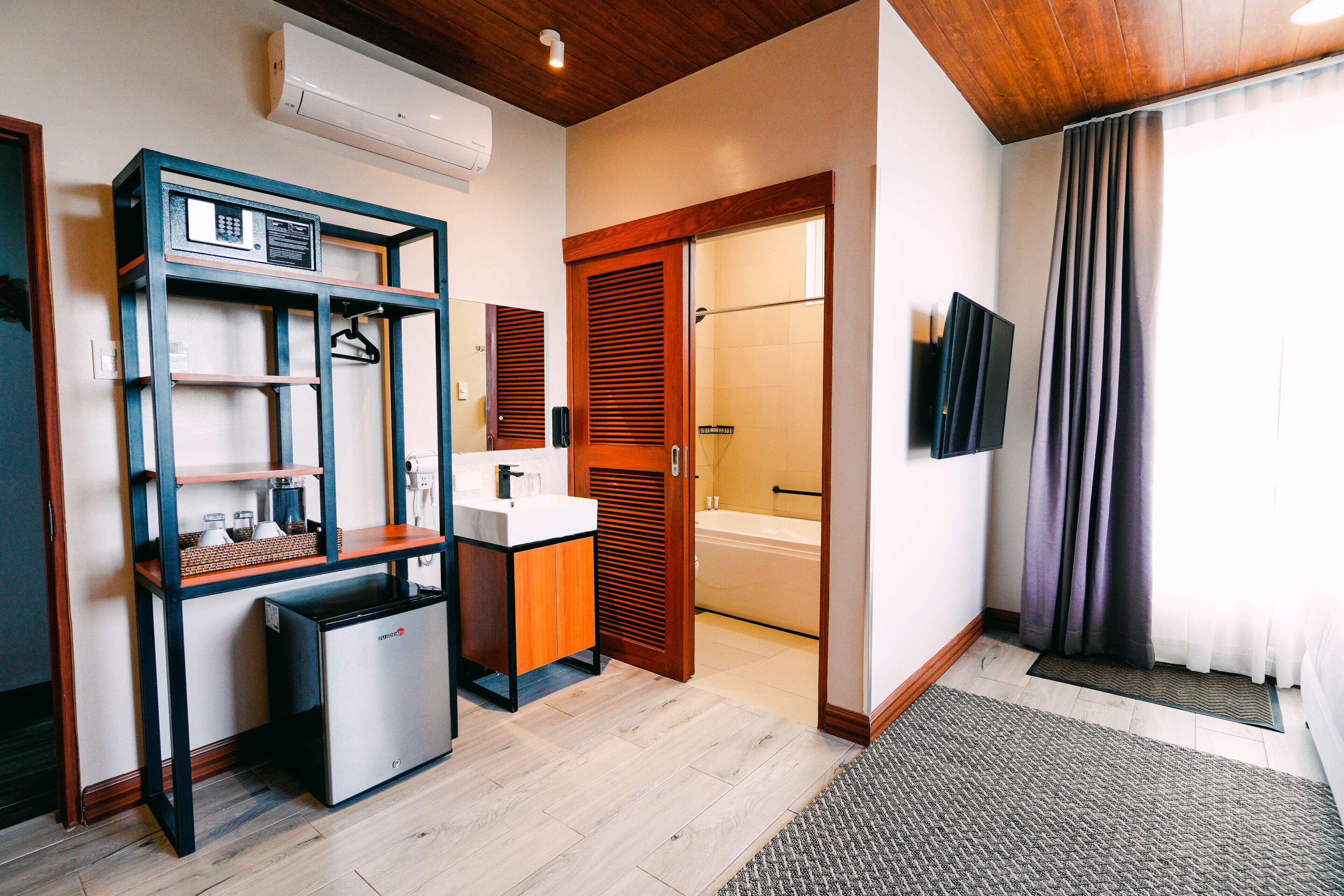 Quarto de hotel compacto com cozinha compacta, área de chuveiro e televisão.
