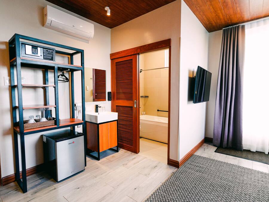 Quarto de hotel compacto com cozinha compacta, área de chuveiro e televisão.