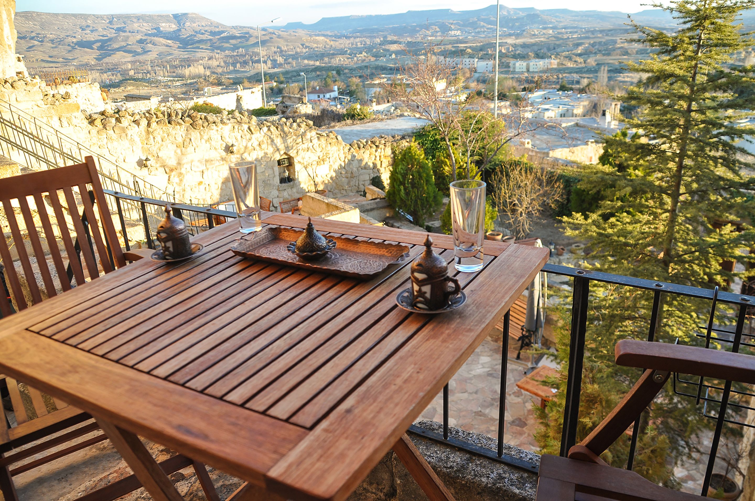 Uma mesa de madeira com vista para um vale e edifícios distantes.