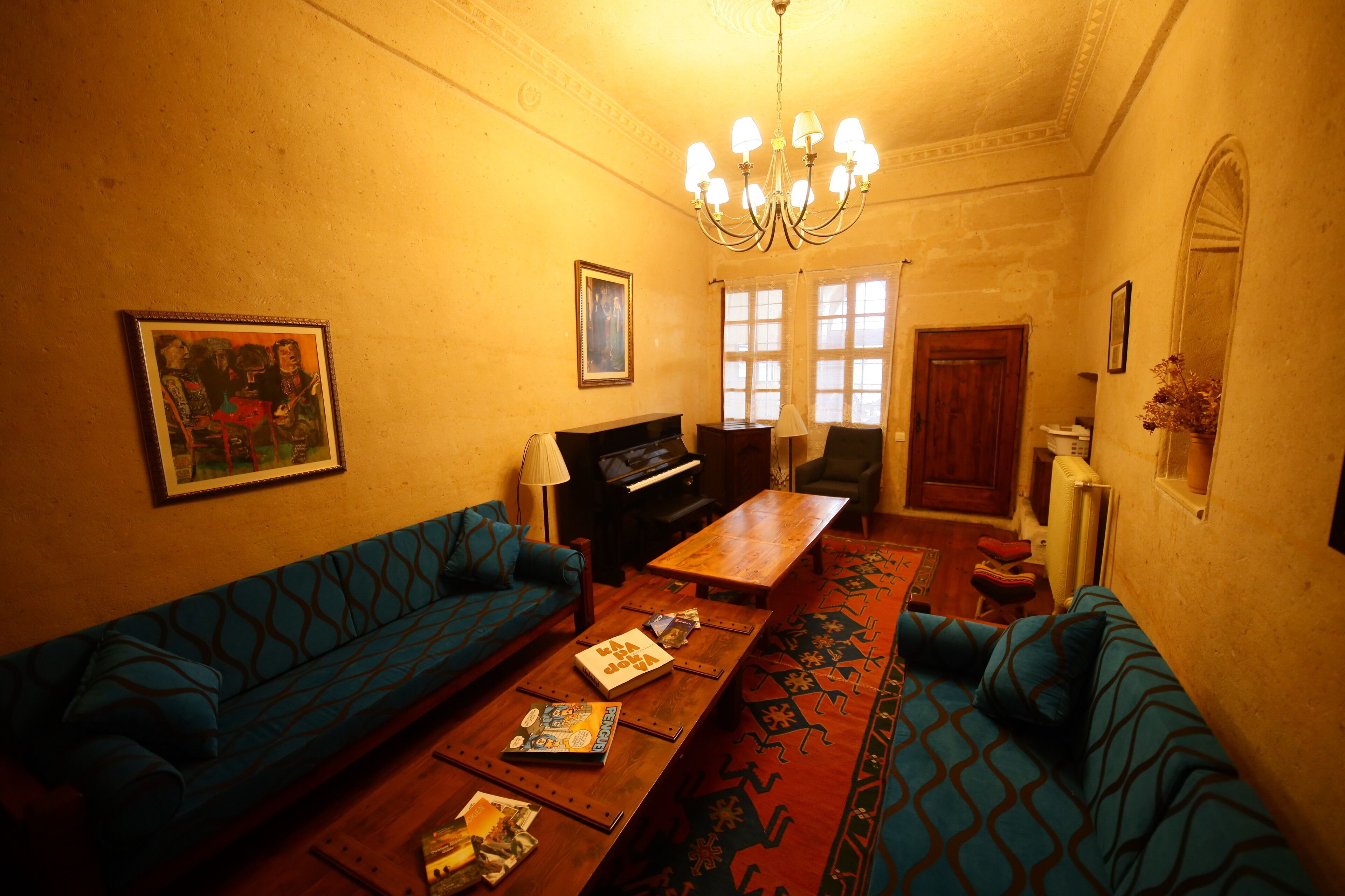 Uma sala de estar com sofá, mesa de centro, piano e lustre.