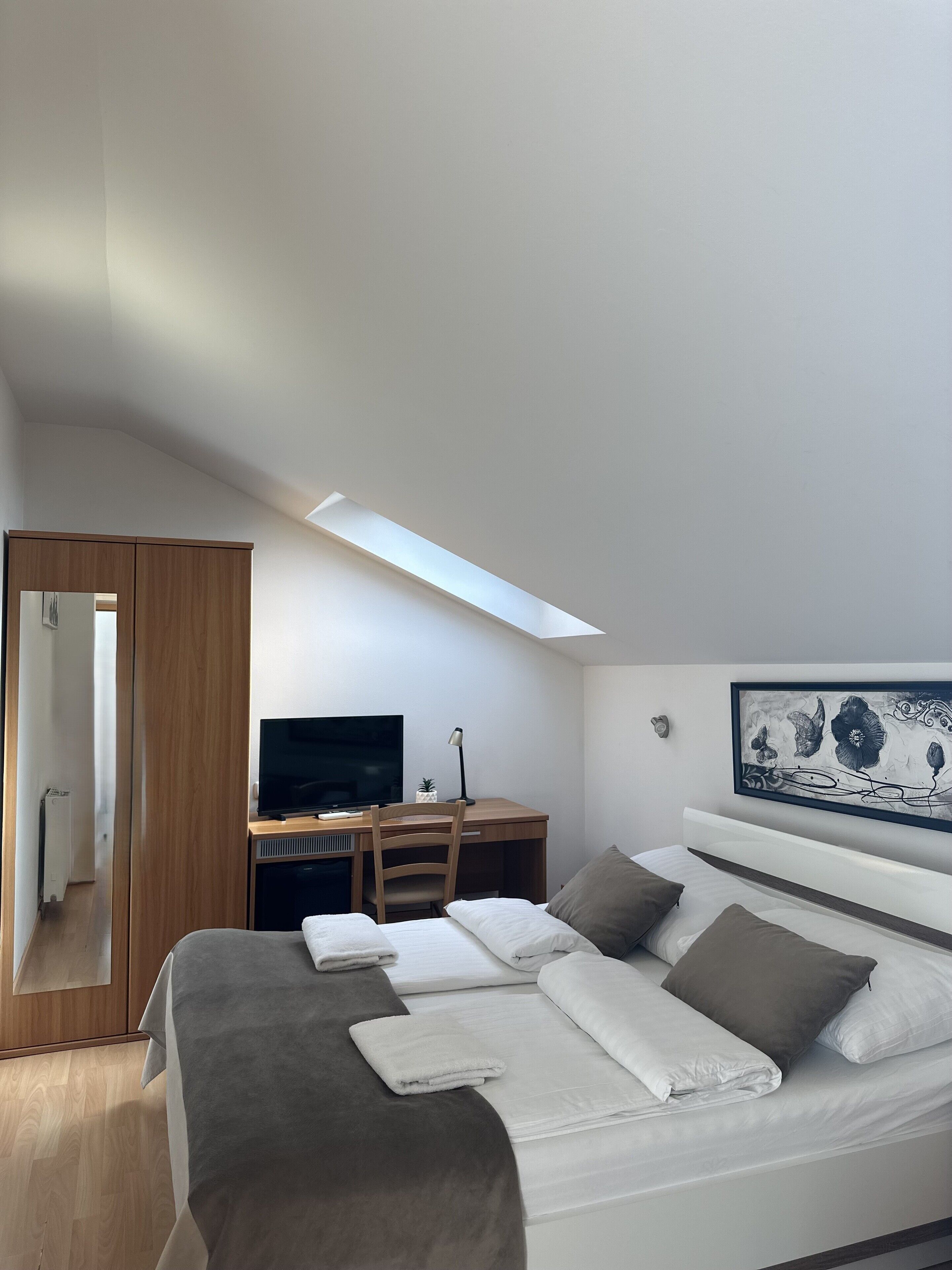 Quarto moderno com cama, escrivaninha e televisão.