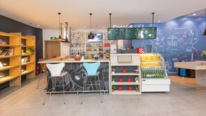 Um café moderno com quadro de cardápio, área de estar e parede decorada com ilustrações de viagens.