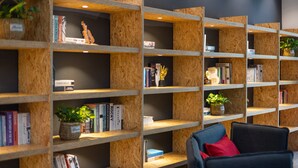 Uma biblioteca moderna com prateleiras de madeira repletas de livros e objetos decorativos.