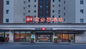 Um hotel com fachada moderna, grandes janelas e uma sinalização chamativa para ibis.